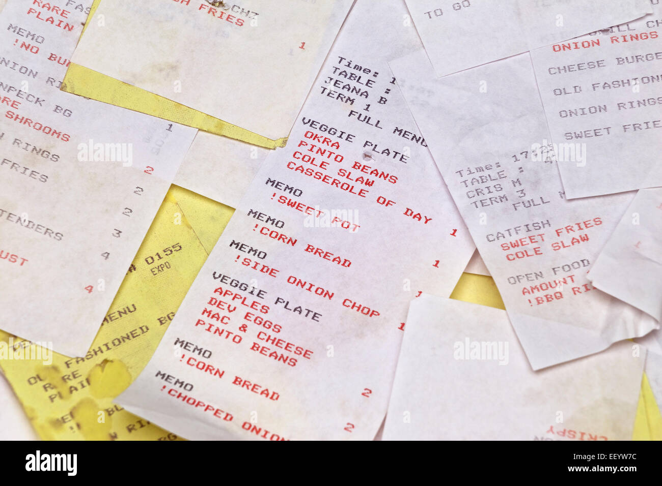 Yellow and white grease stained restaurant food order tickets in a pile ...