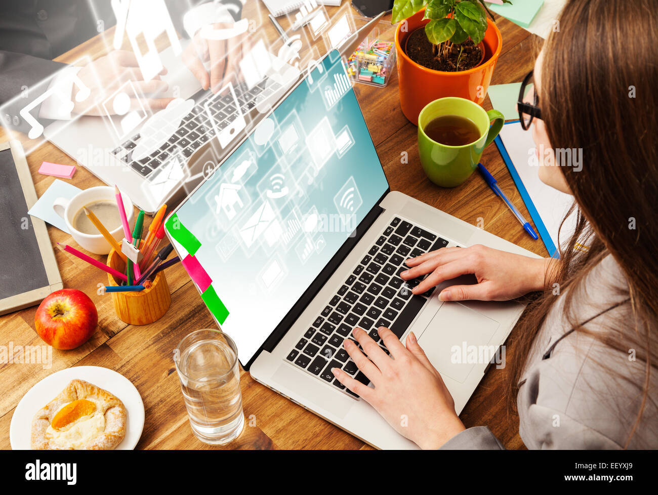 Woman working with laptop placed on wooden desk with digital scheme ...
