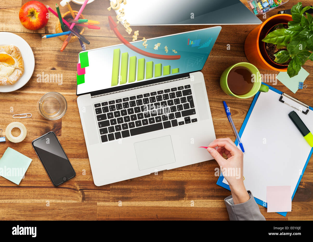 Woman working with laptop placed on wooden desk with digital scheme ...