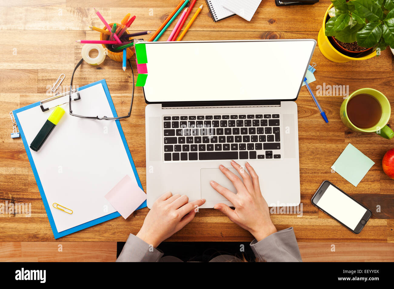 Woman working with laptop placed on wooden desk. Shot from aerial view ...