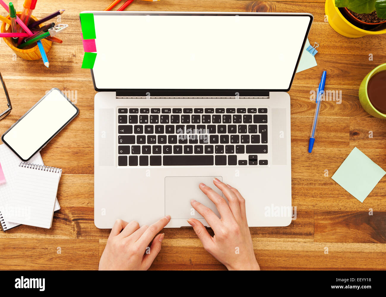Woman working with laptop placed on wooden desk. Shot from aerial view ...