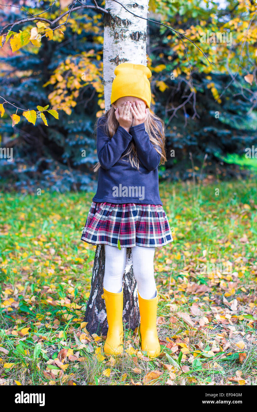 Little girl playing hide and seek in autumn forest Stock Photo - Alamy