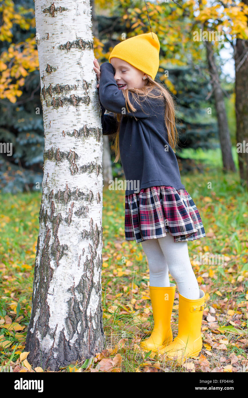 Little girl playing hide and seek in autumn forest outdoors Stock Photo ...