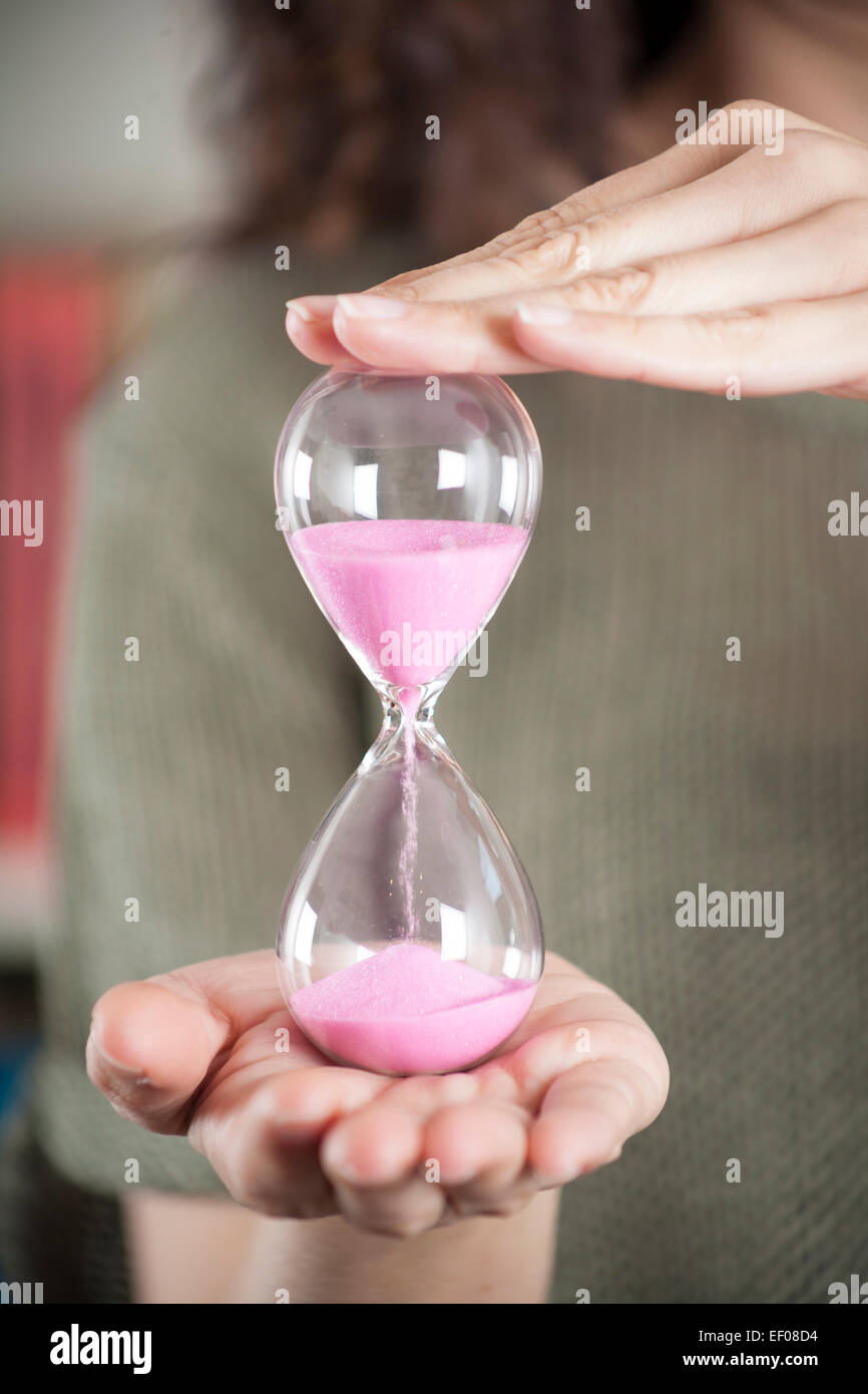 pink sand clock in woman hands over green background Stock Photo - Alamy