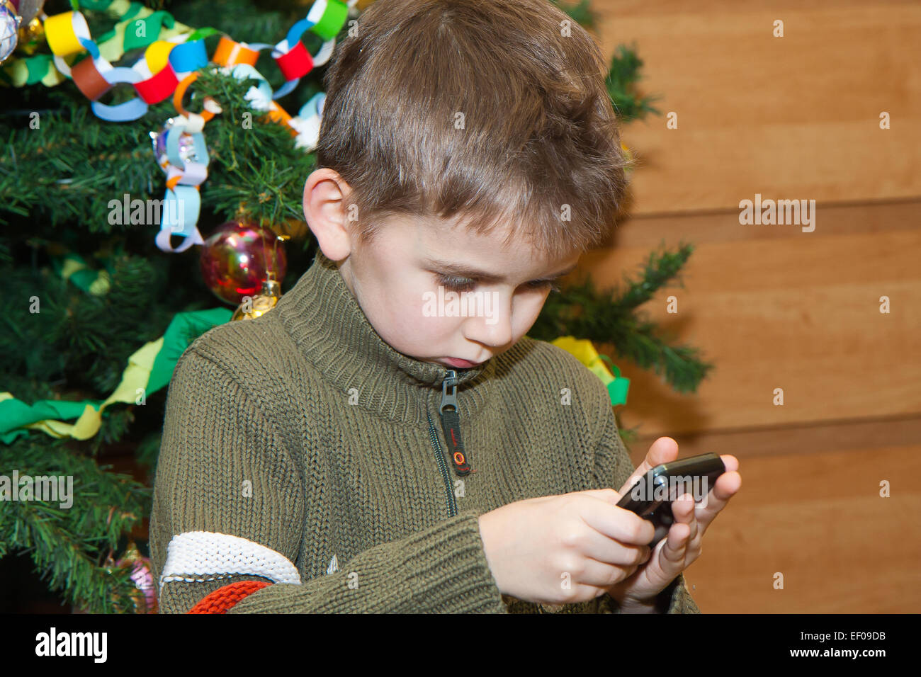 A small boy playing with a mobile phone which he get as a Christmas ...