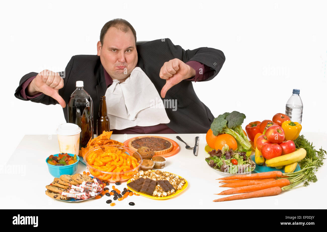 Overweight man sitting at a table full of food Stock Photo - Alamy