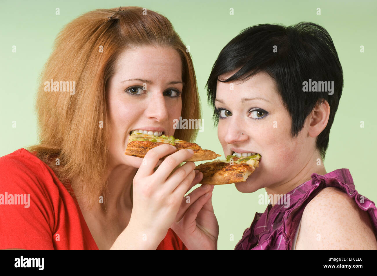 Two women eating pizza Stock Photo - Alamy