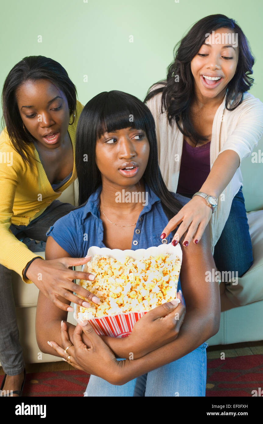 Three friends eating popcorn Stock Photo - Alamy