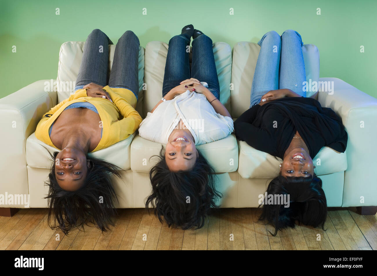 Three friends lying upside down on couch Stock Photo - Alamy