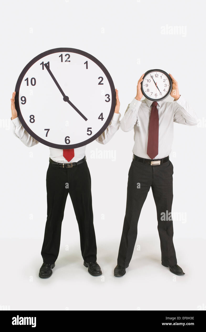 Businessmen holding clocks in front of their faces Stock Photo - Alamy