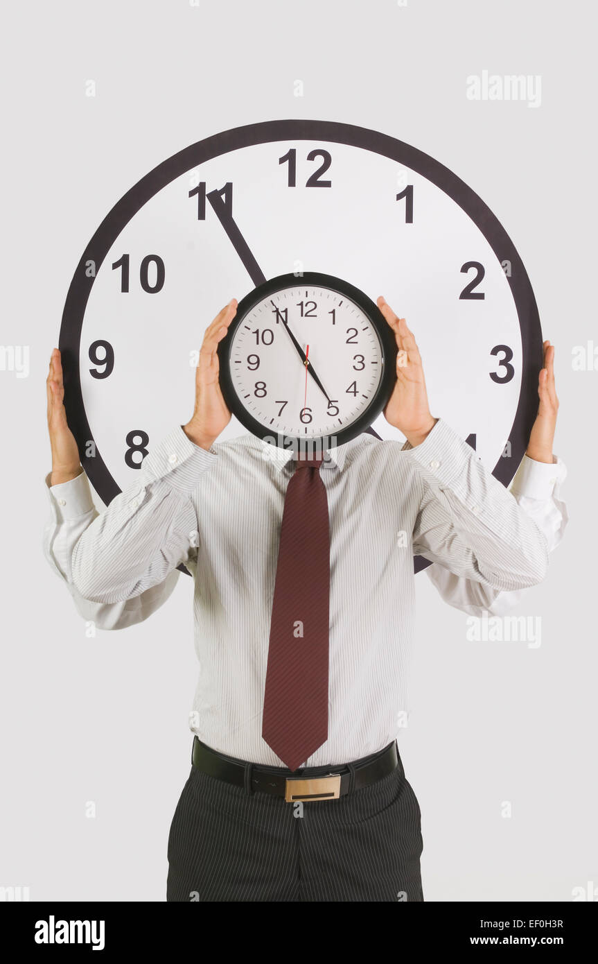 Businessmen holding clocks in front of their faces Stock Photo - Alamy