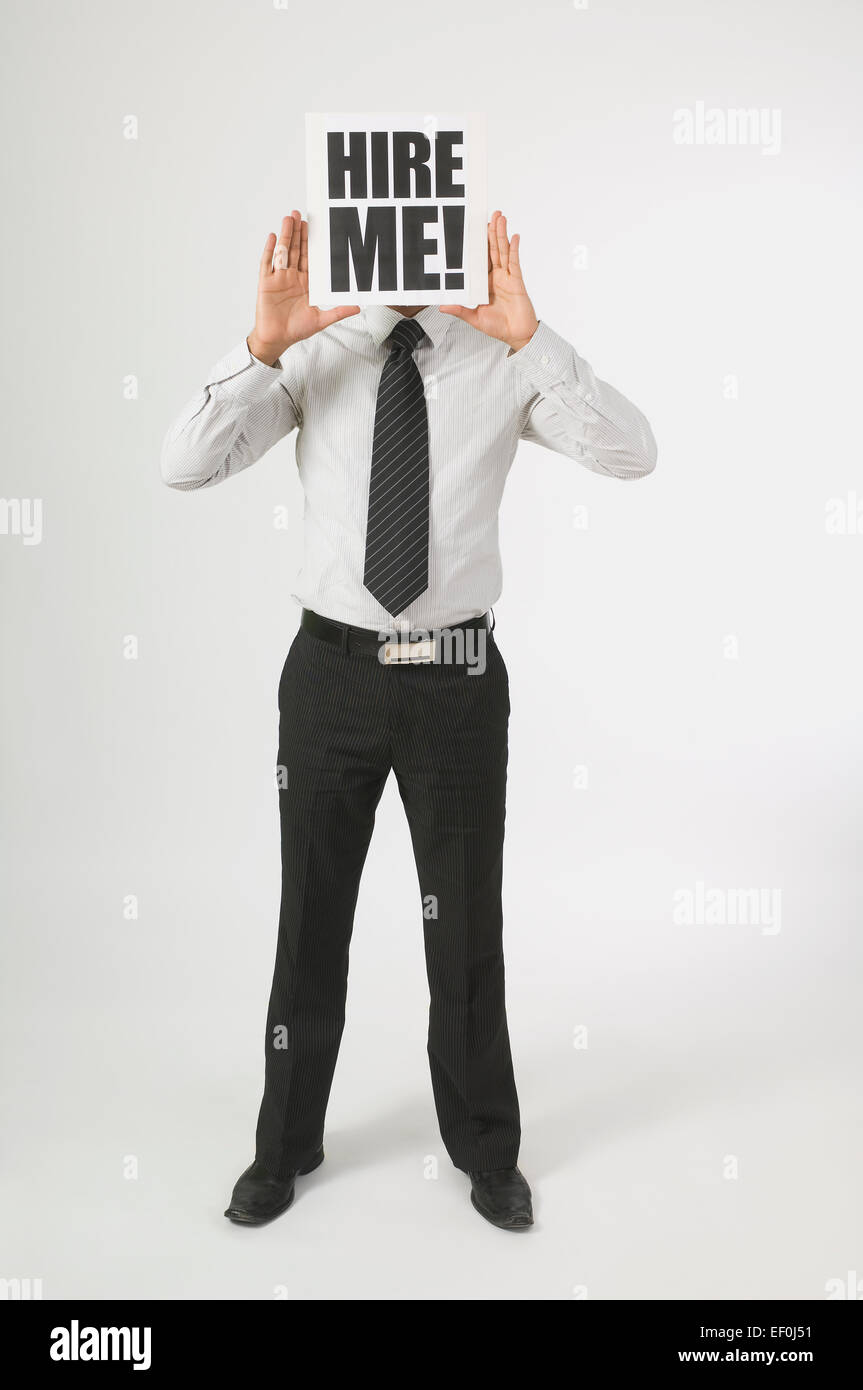 Man holding a hire me sign in front of his face Stock Photo - Alamy