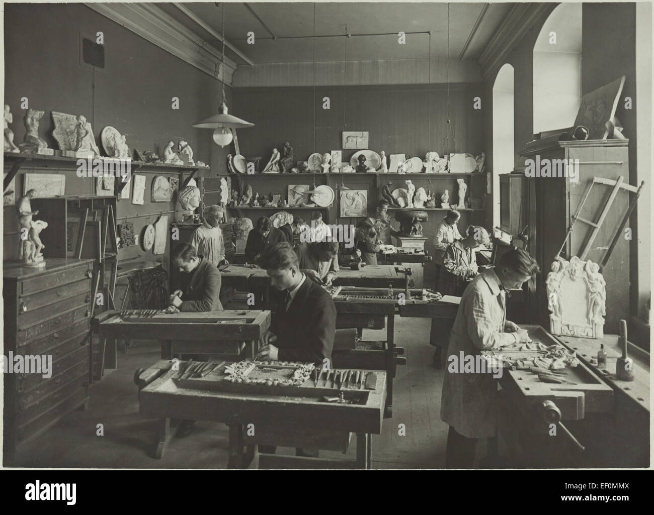 This image shows a wood carving class, where students are learning the ...