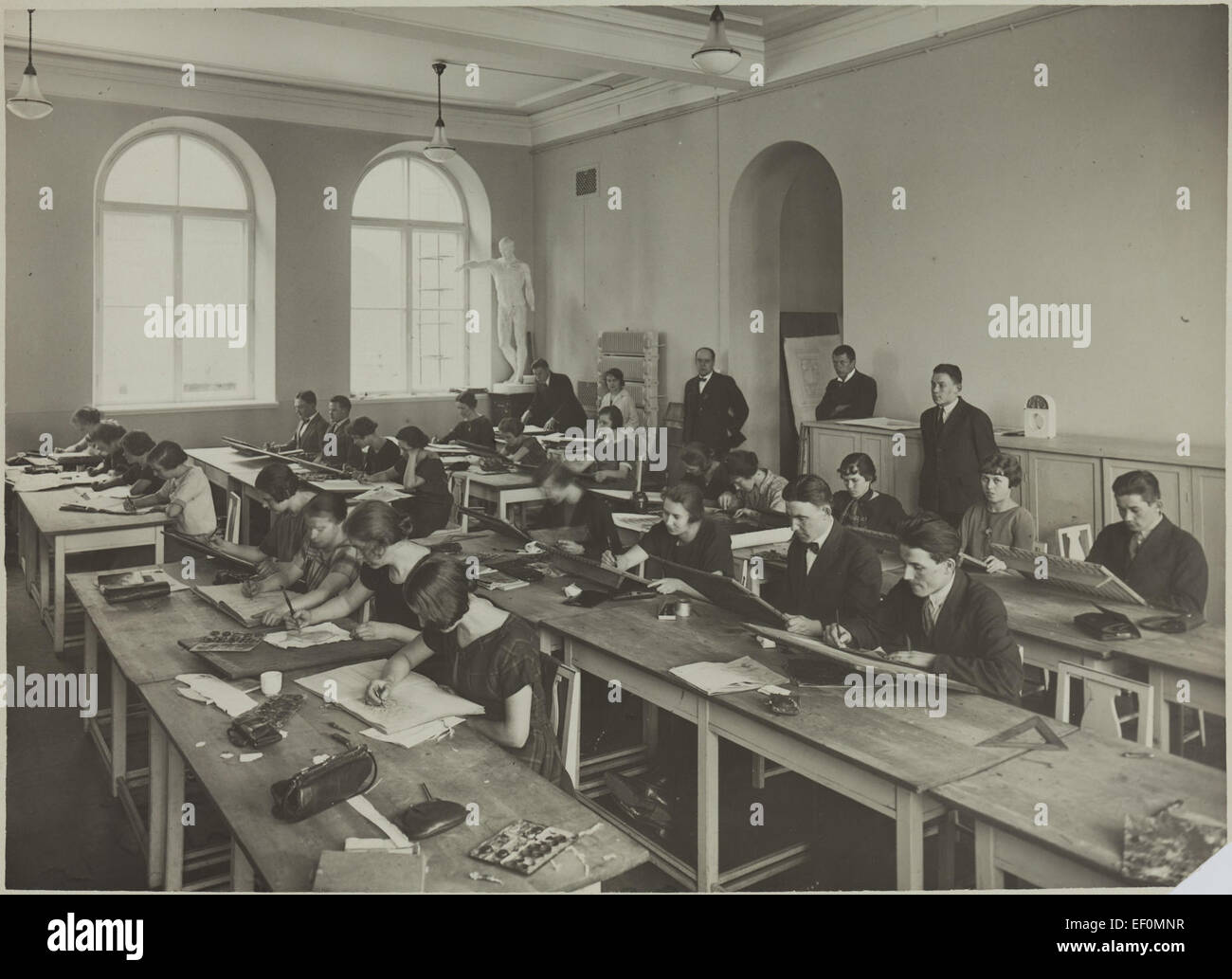 This image depicts a drawing class, likely from the early 20th century ...