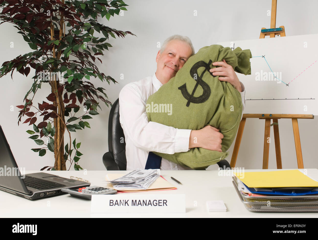 Bank manager hugging bag of money Stock Photo - Alamy