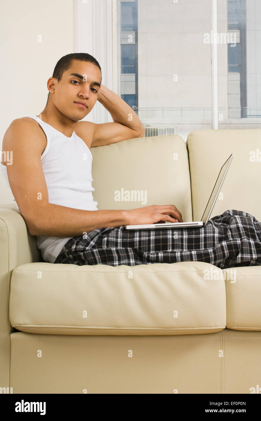 Man using laptop while sitting on couch Stock Photo - Alamy