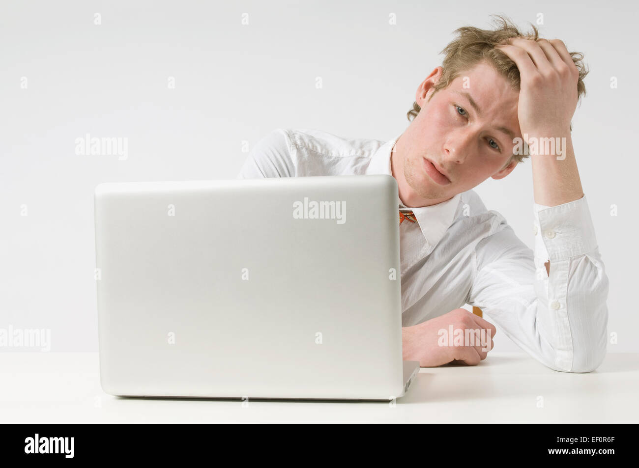 Tired man looking at laptop Stock Photo - Alamy
