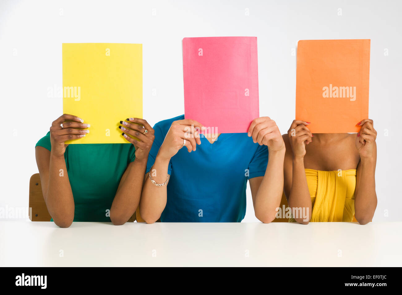 Three people holding colorful duo-tangs in front of their faces Stock ...