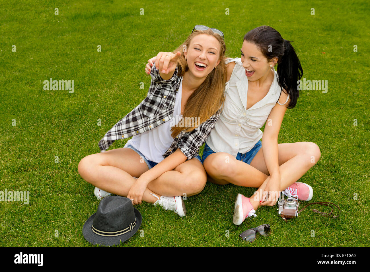 Female best friends sitting on the grass and having a good time Stock ...