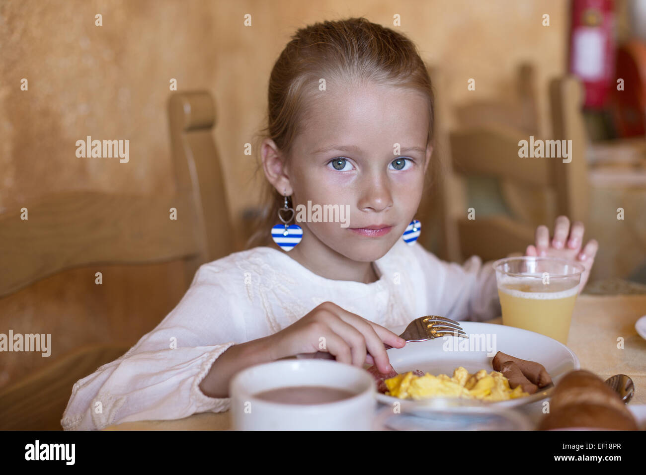 Adorable little girl having breakfast at indoor cafe Stock Photo - Alamy