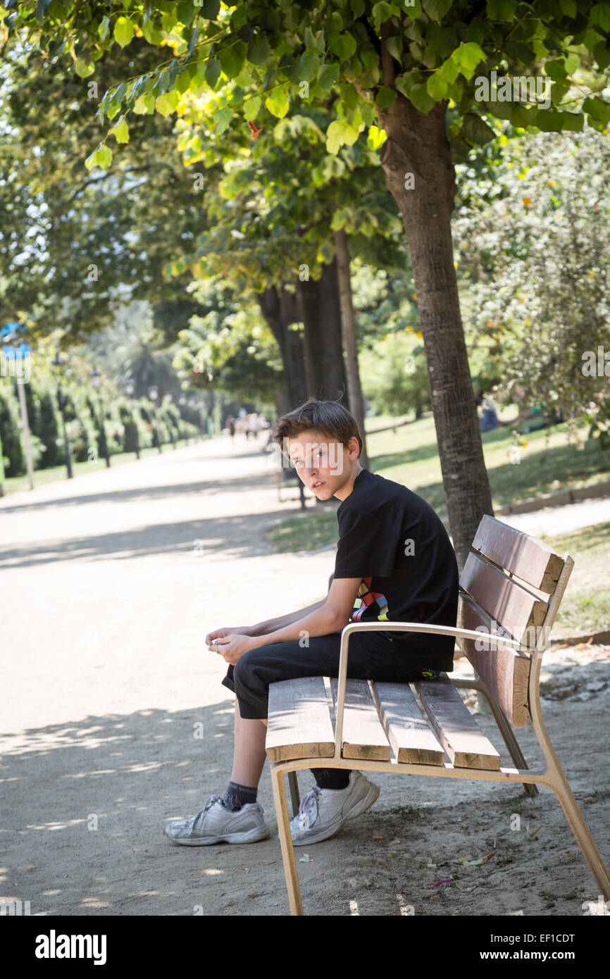 teenage boy sitting on a bench in a park Stock Photo - Alamy