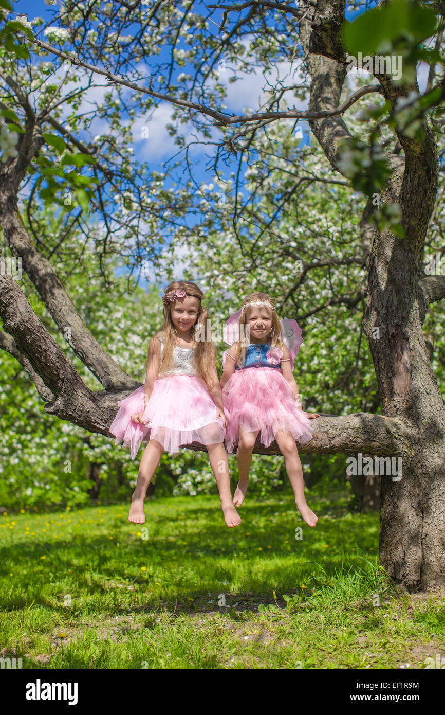 Little adorable girls sitting on blossoming apple tree Stock Photo - Alamy