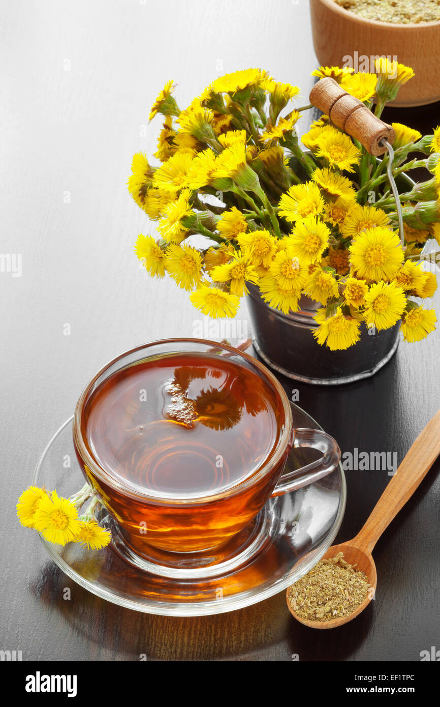 healthy tea, bucket with coltsfoot flowers and mortar on table, herbal ...