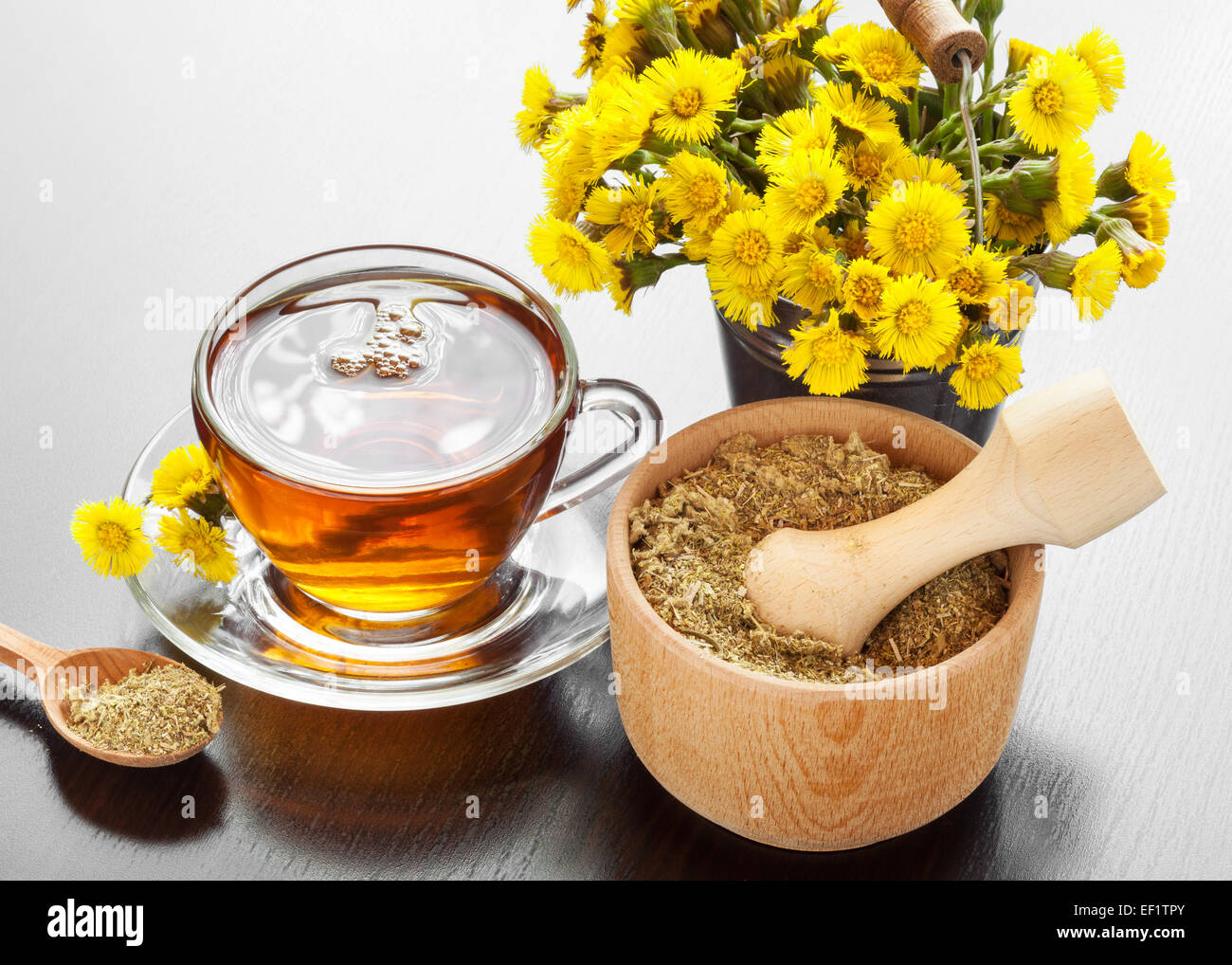 healthy tea in glass mug, bucket with coltsfoot flowers and mortar on ...