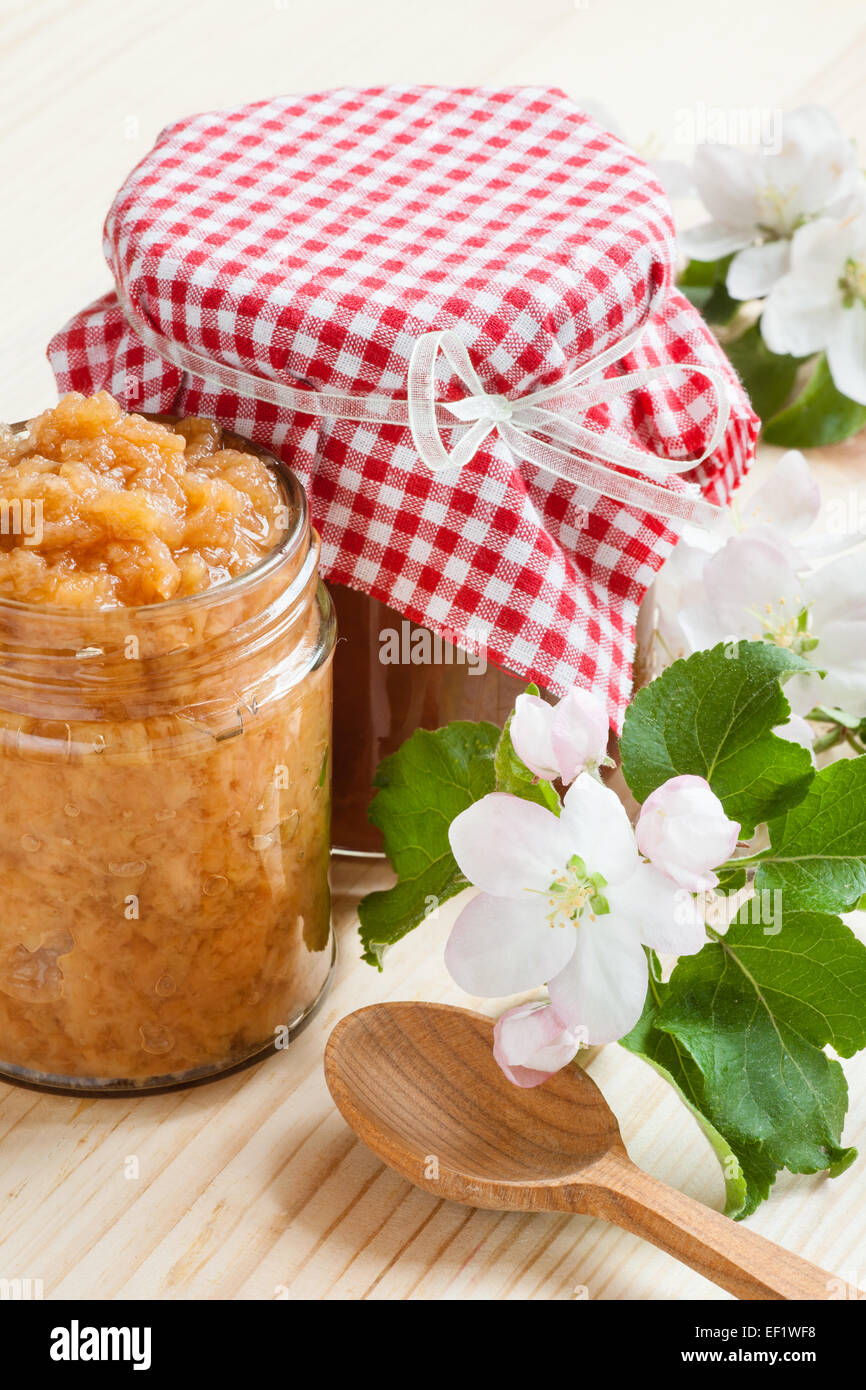 apple jam and puree in jars and wooden spoon on kitchen table Stock ...
