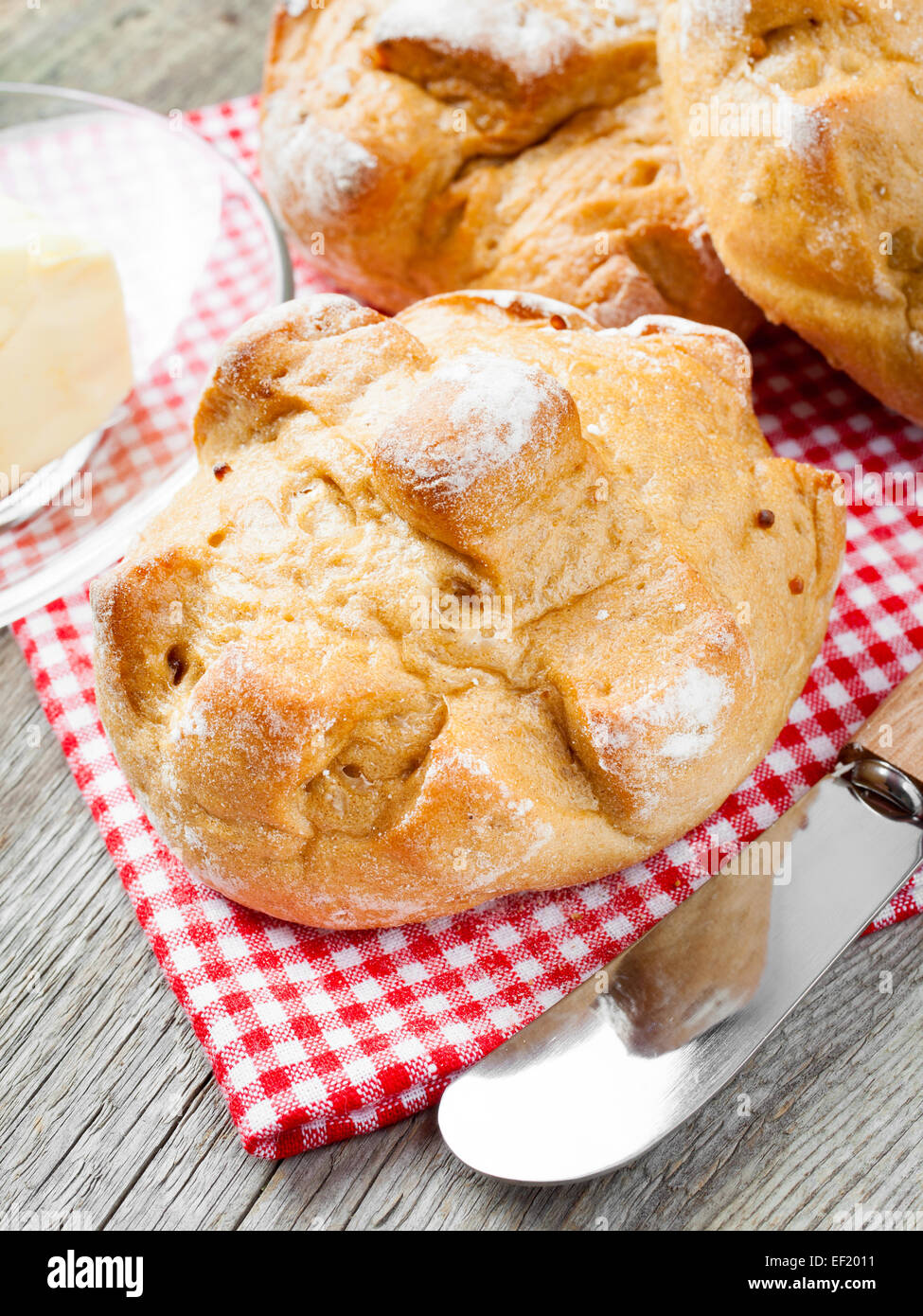 Wholemeal french buns and butter on wooden kitchen table Stock Photo ...
