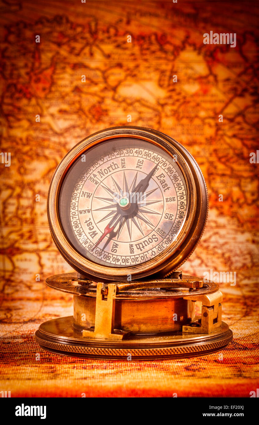 Vintage still life. Vintage compass lies on an ancient world map in ...