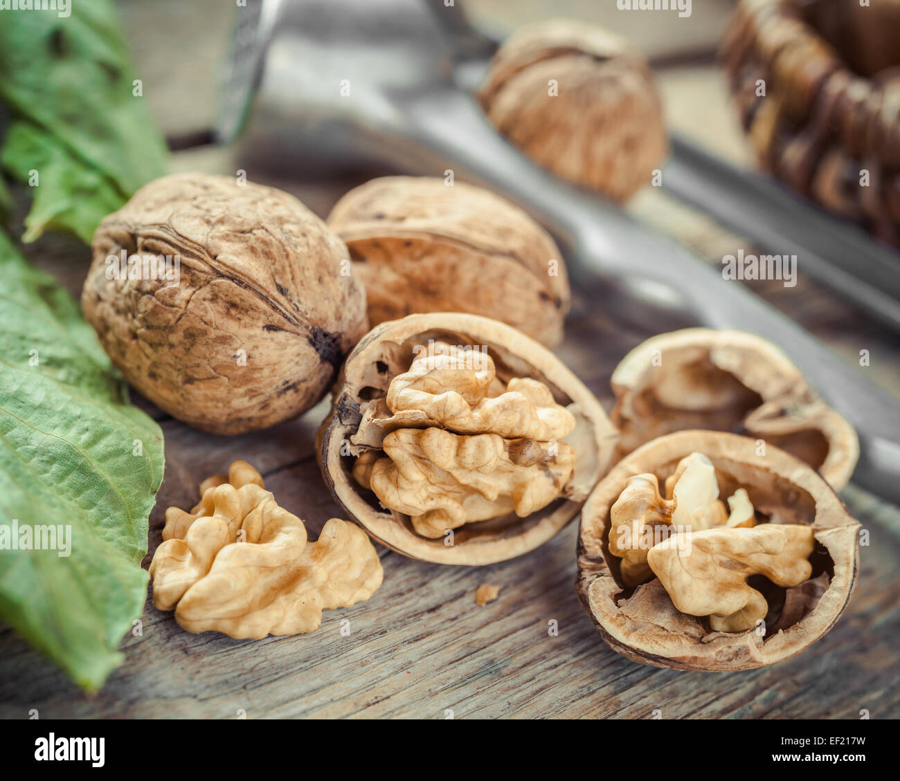 Open walnut close up, nutcracker and basket on wooden background ...