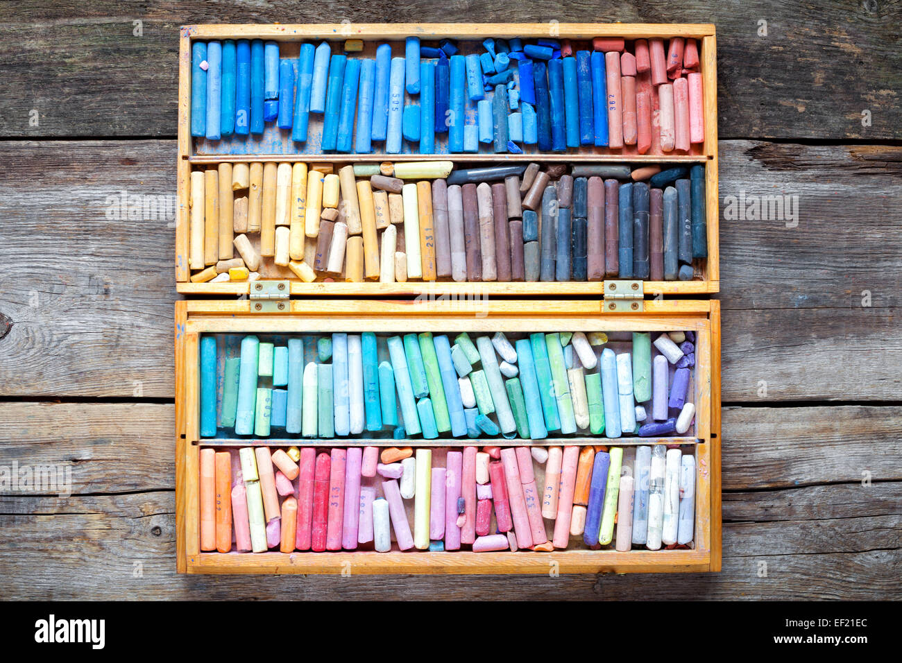 Set of multicolored pastel crayons in open wooden artist box on rustic ...