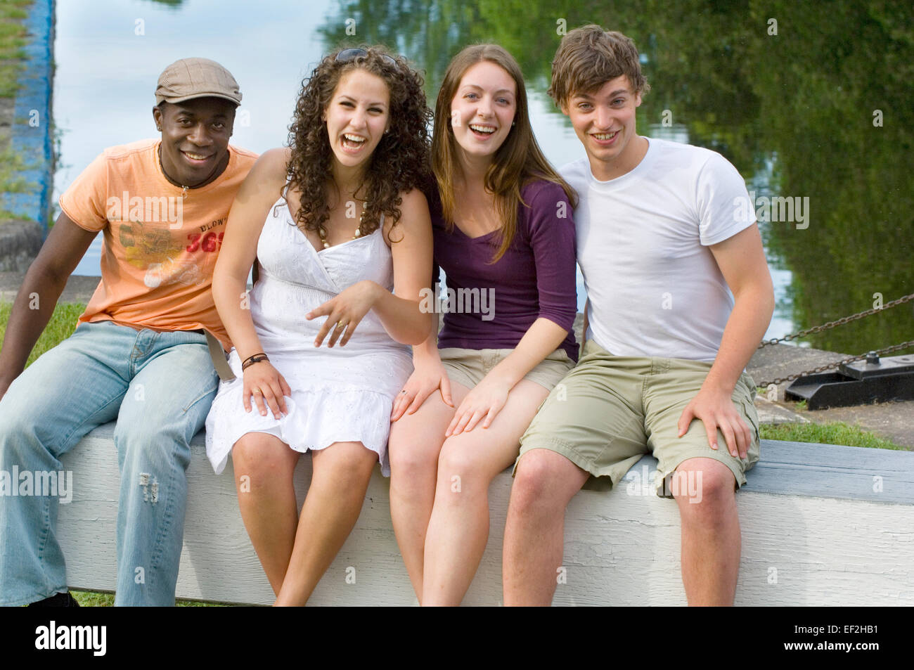 Four friends at a park laughing Stock Photo - Alamy