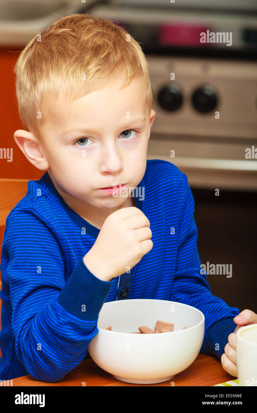 Happy childhood. Blond boy kid child eating corn flakes cereal with ...
