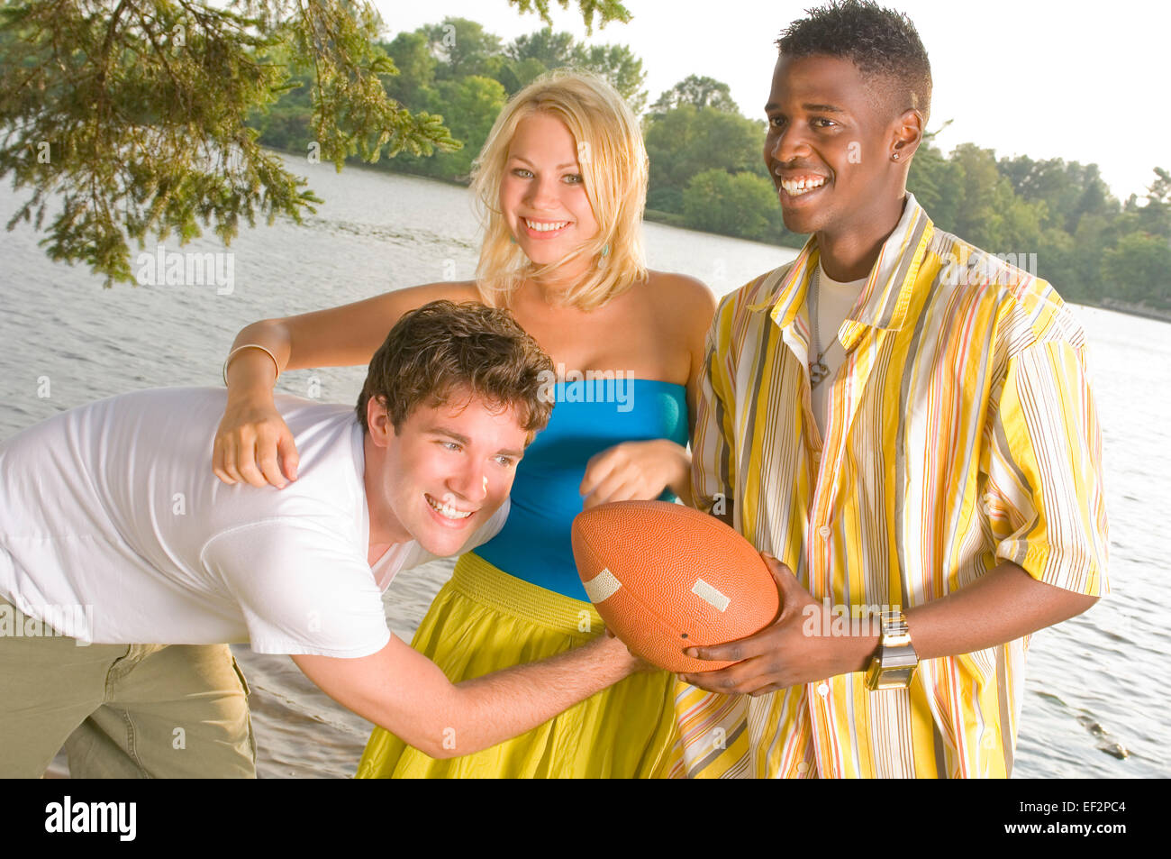 Three friends playing football Stock Photo - Alamy