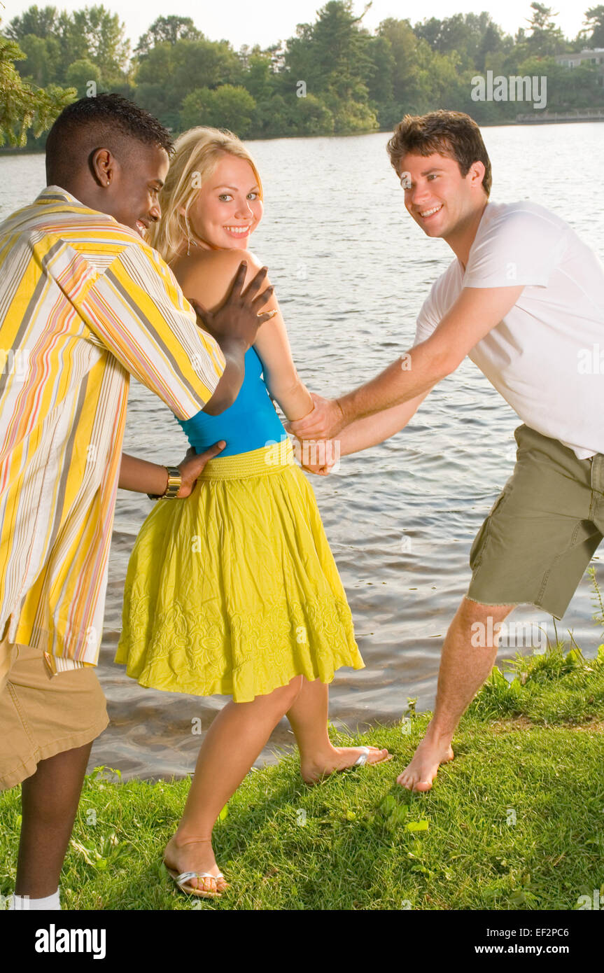 Two teenage boys about to push a girl into the water Stock Photo - Alamy