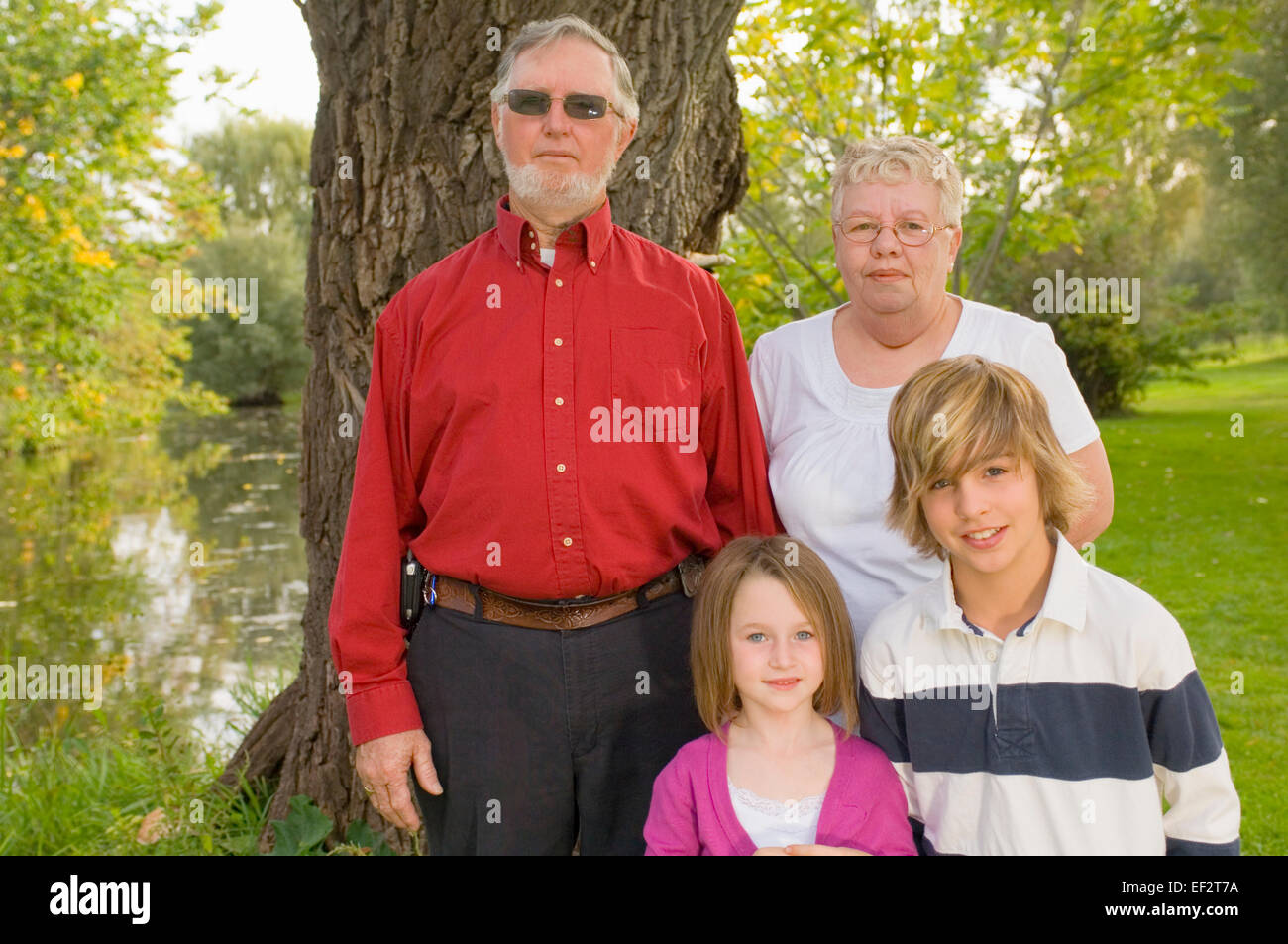 Family standing in front of tree Stock Photo - Alamy