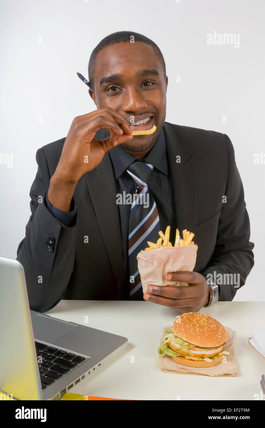 Businessman eating lunch at his desk Stock Photo - Alamy