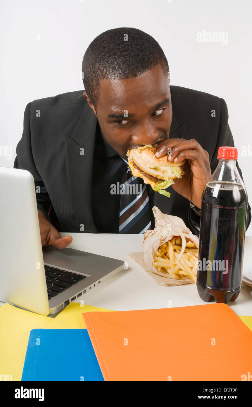 Businessman eating lunch at his desk Stock Photo - Alamy