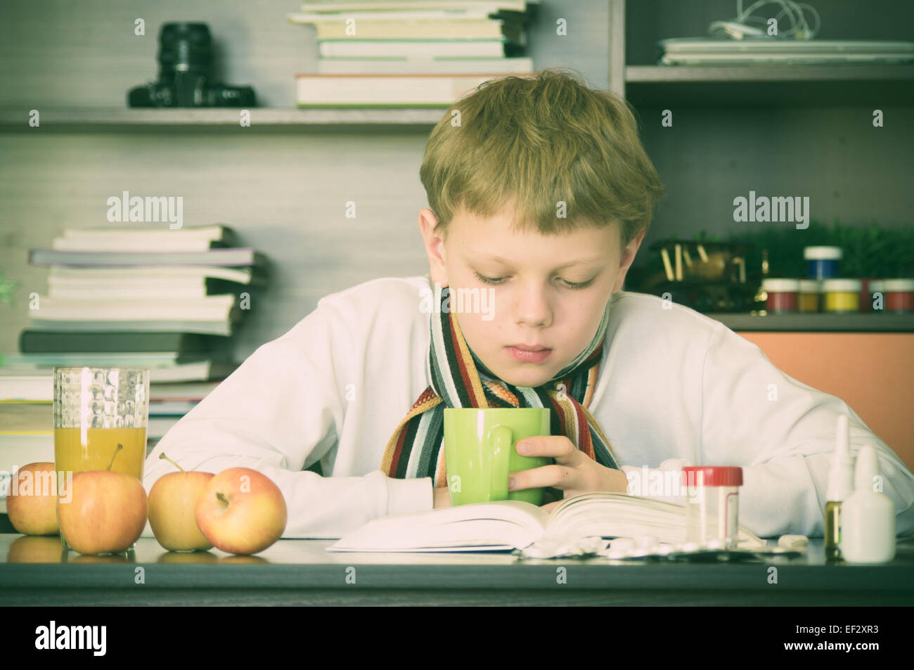 Ill boy with flu to study at home. On the table medicines, fruits and ...