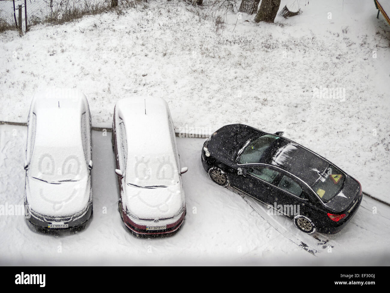 Funny faces drawn on the snow on the windshield of the car parked in ...