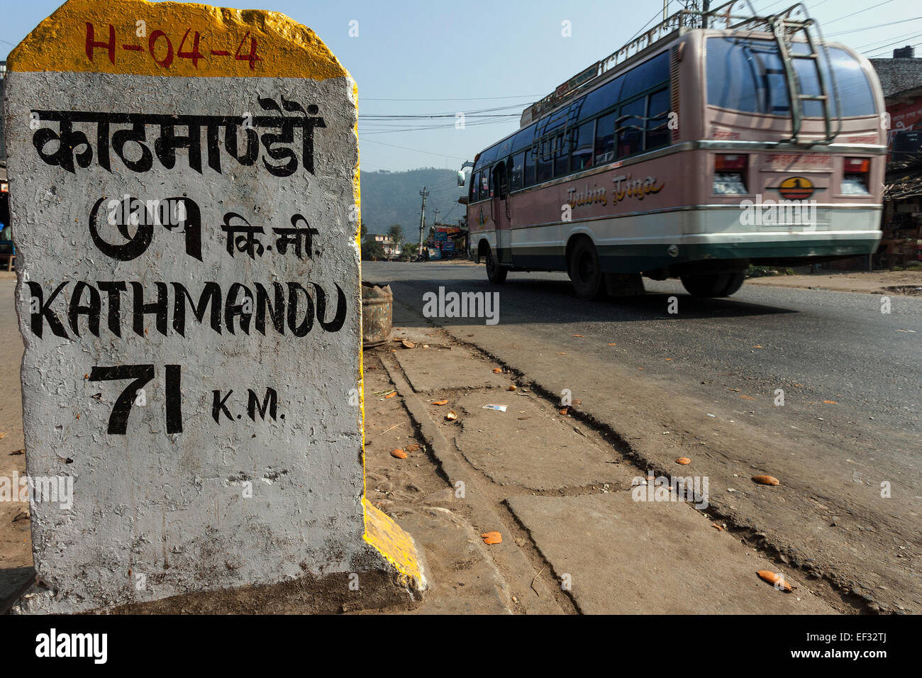 Milestone at the roadside with a Nepalese bus passing, Patauri, Nepal ...