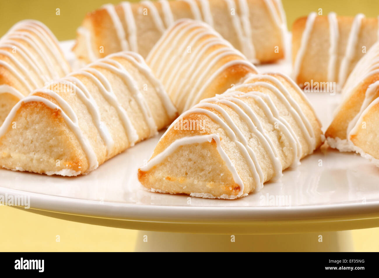 Danish finger macaroons on a white cake stand over a green background ...