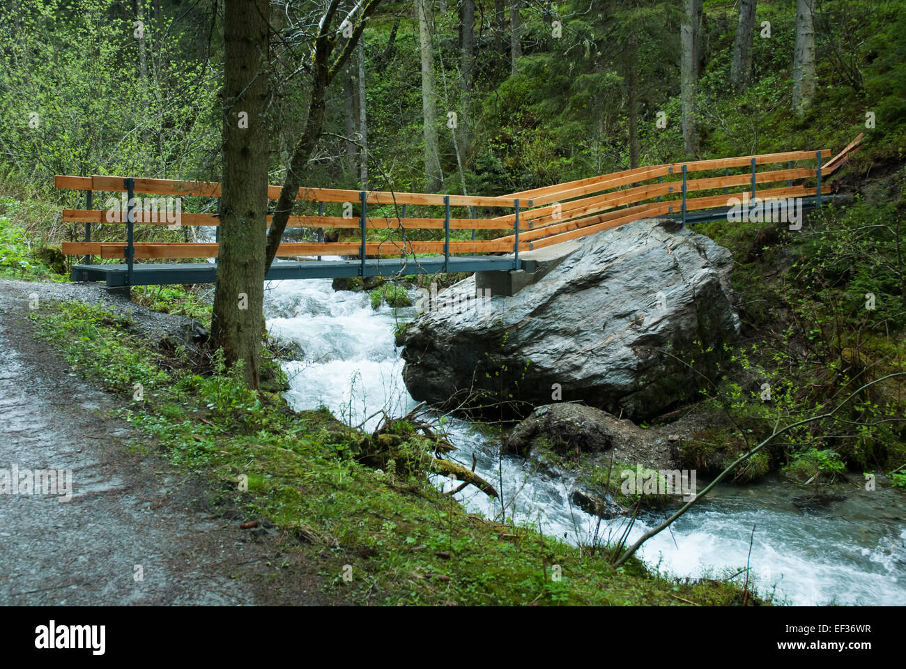 The bridge over Voldertalbach in the Tux Alps of Austria provides a ...