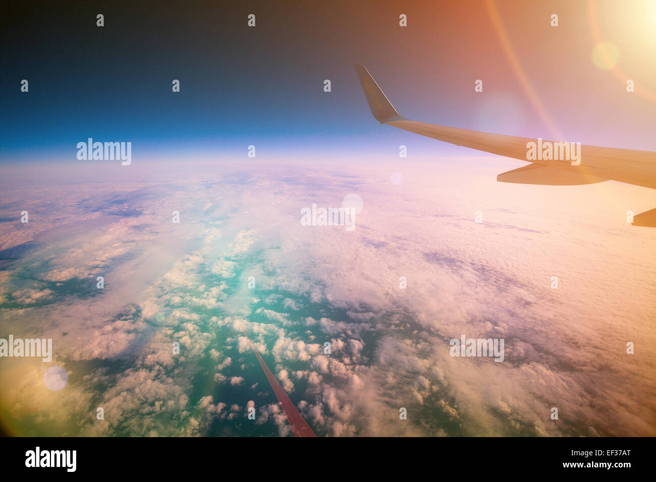 Airplane flying over clouds at sunrise Stock Photo - Alamy