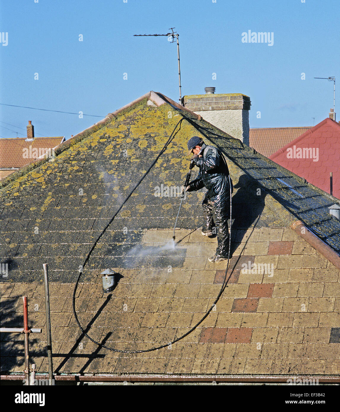 Cleaning roof of lichen and moss with pressure spray Stock Photo - Alamy