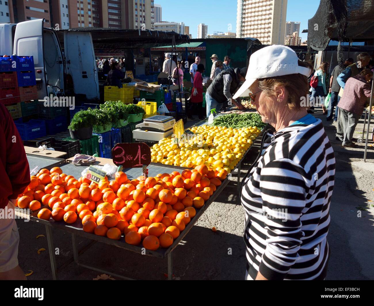Fruit stall with a lady looking at the Oranges Stock Photo - Alamy
