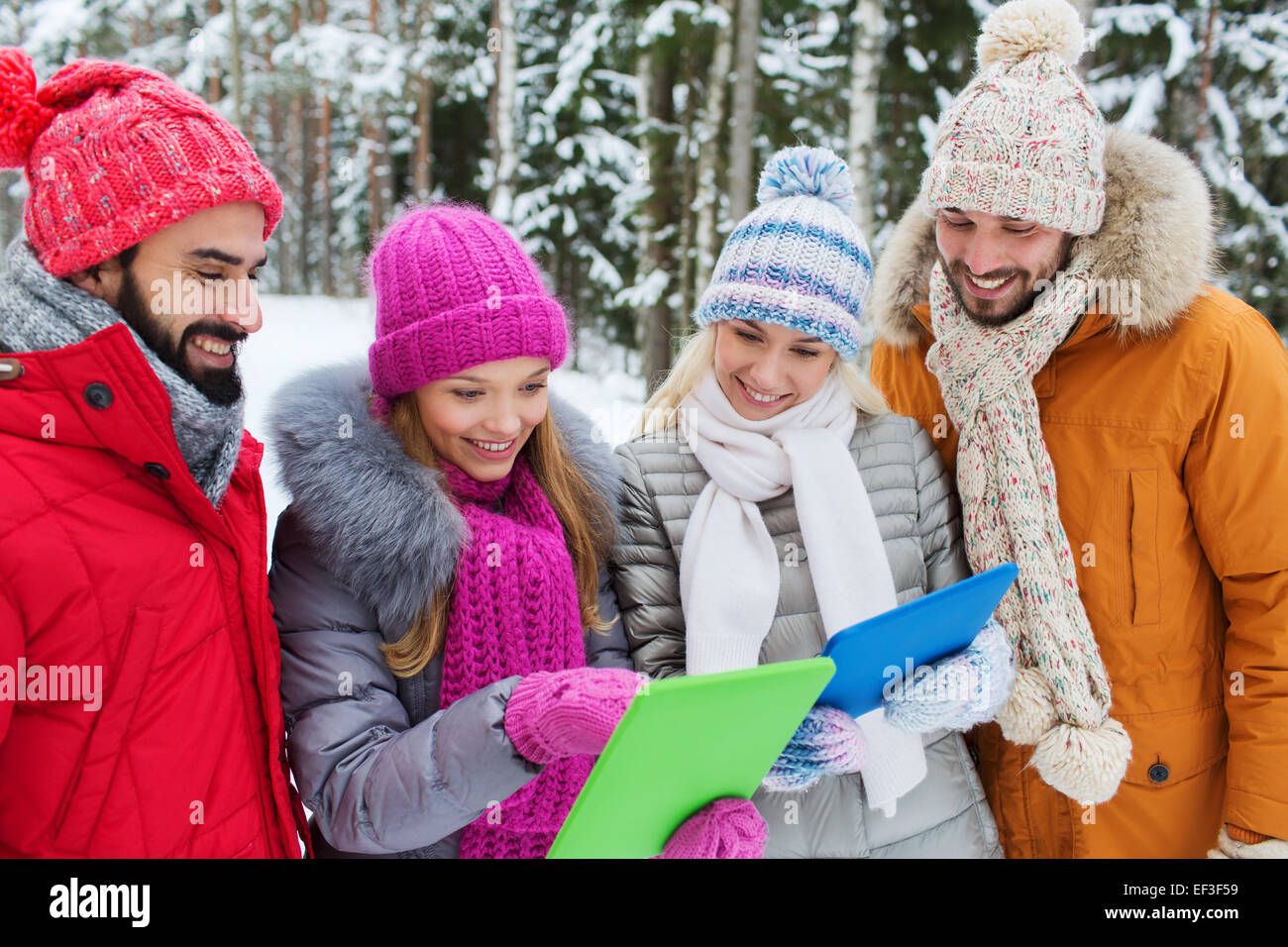 smiling friends with tablet pc in winter forest Stock Photo - Alamy