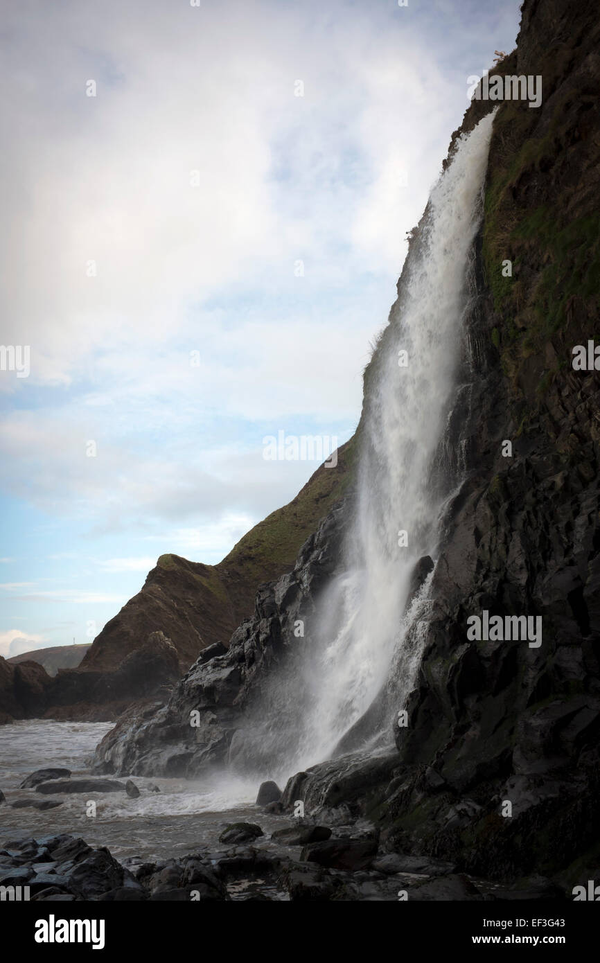 A waterfall cascading over rocks on to the beach in the village of ...